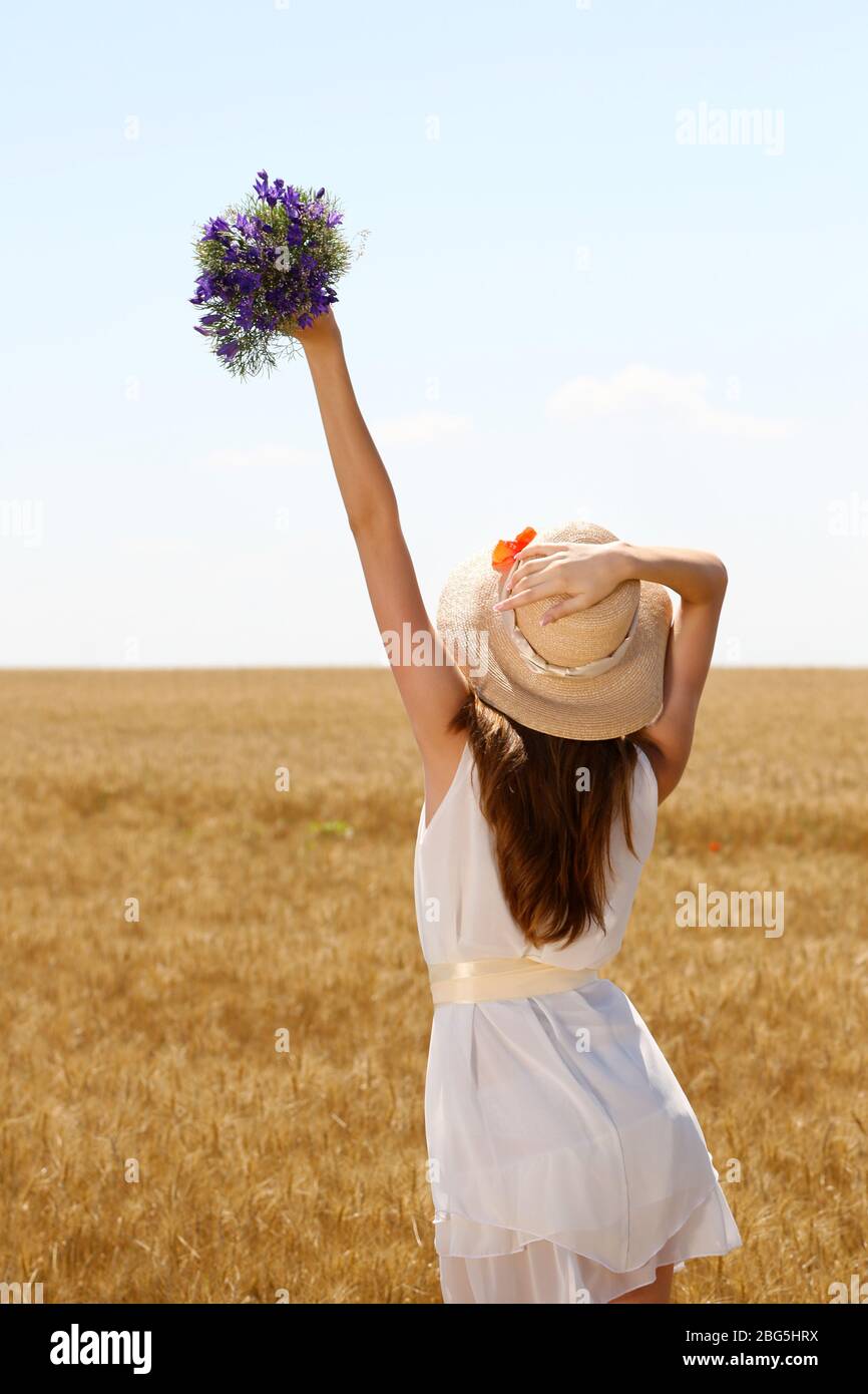 Portrait of beautiful young woman with flowers in the field Stock Photo ...