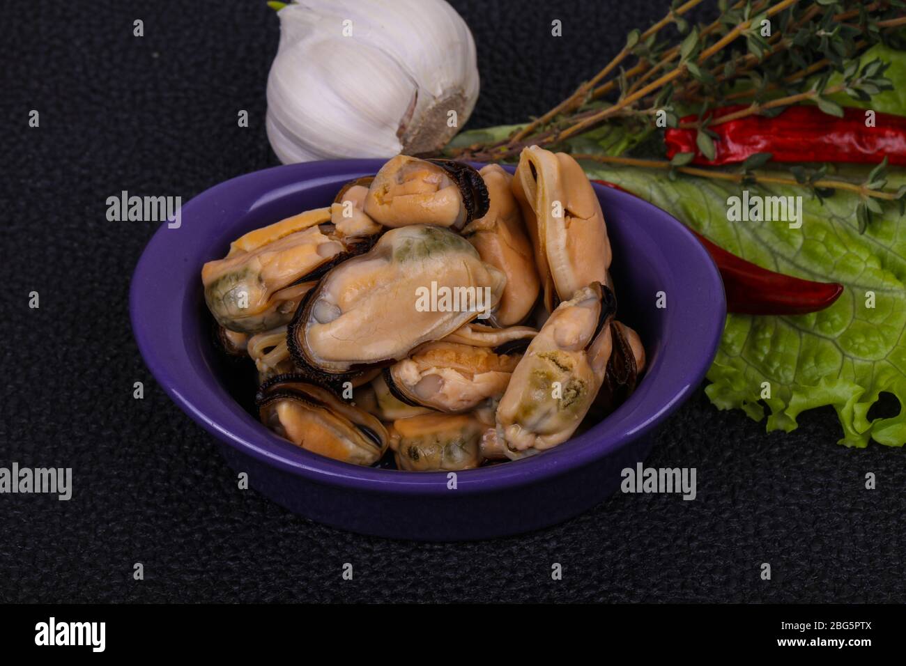 Pickled mussels in the bowl served pepper, garlic and salad leaves ...