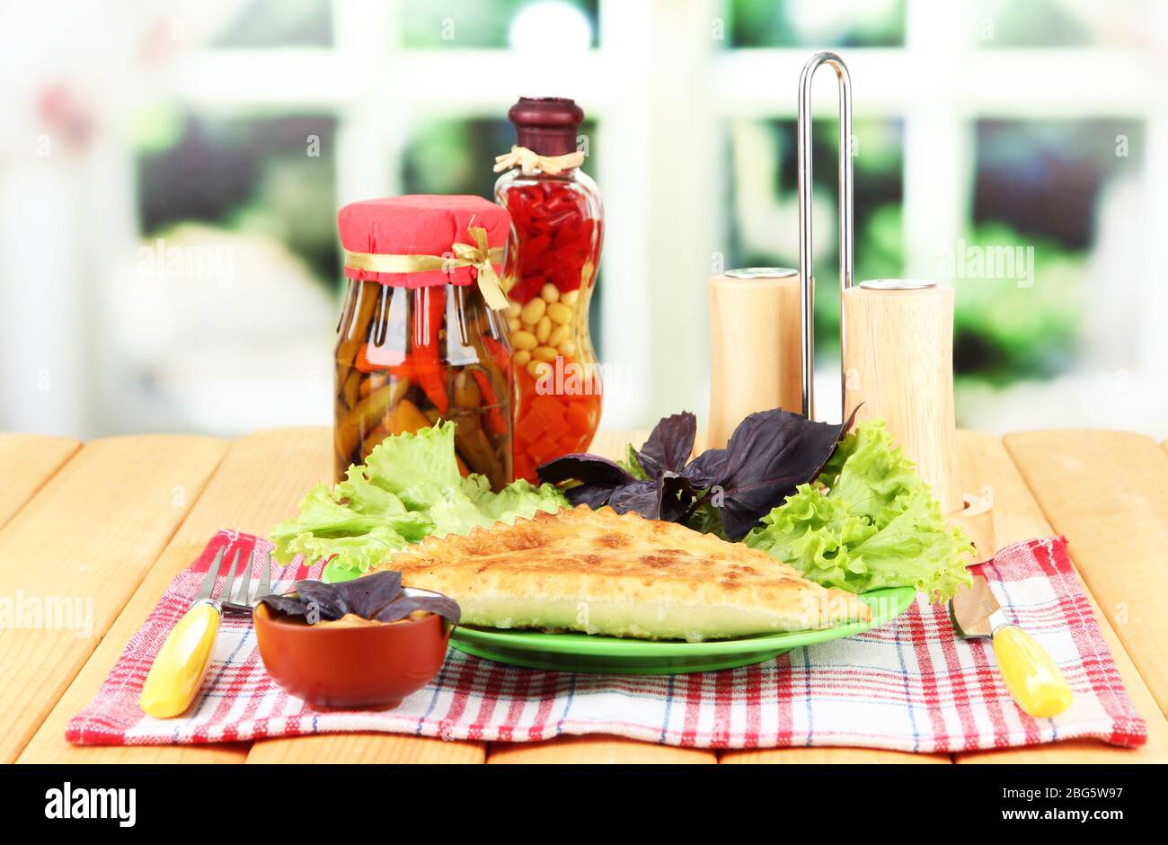 Tasty chebureks with fresh herbs on plate,on wooden table, on bright ...