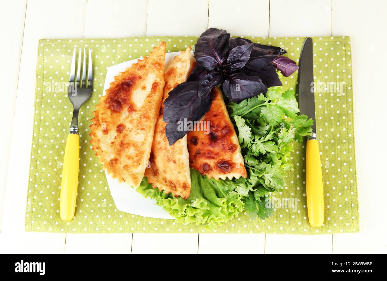 Tasty chebureks with fresh herbs on plate,on color wooden background ...