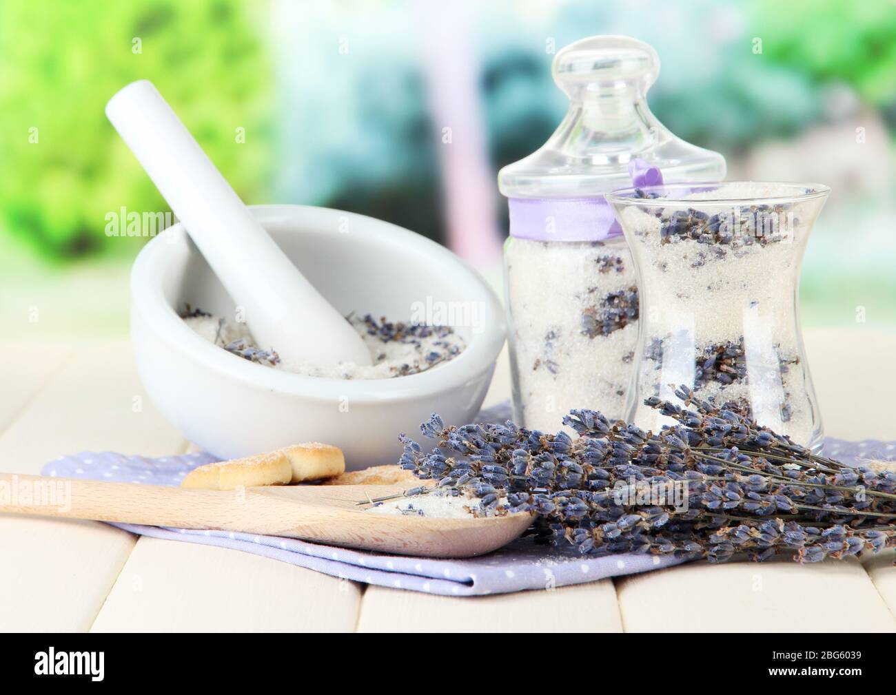 Still life with jar of lavender sugar, mortar and fresh lavender flowers on bright background ...