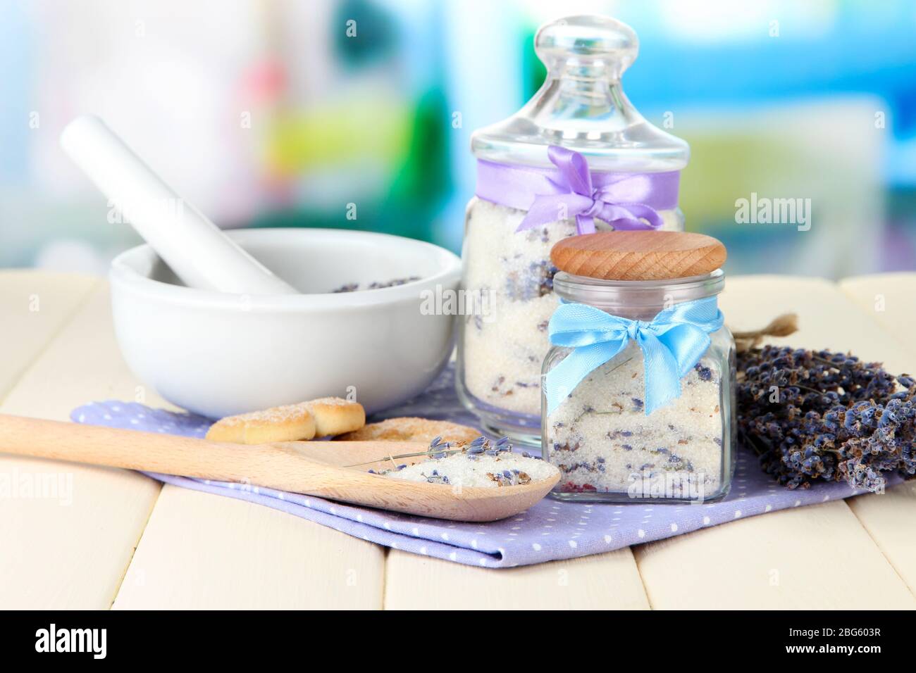 Still life with jar of lavender sugar, mortar and fresh lavender flowers on bright background ...