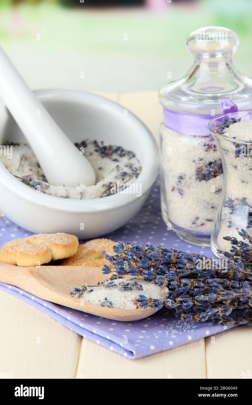 Still life with jar of lavender sugar, mortar and fresh lavender flowers on bright background ...