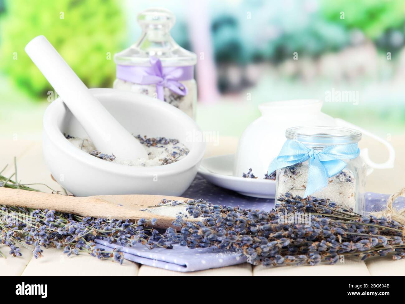 Still life with jar of lavender sugar, mortar and fresh lavender flowers on bright background ...
