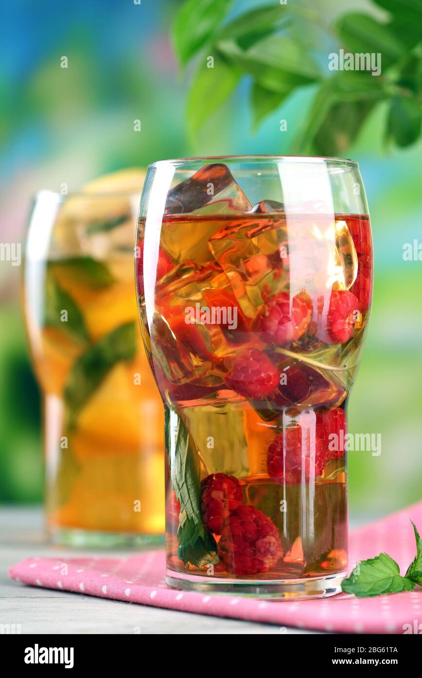 Iced tea with raspberries, lemon and mint on wooden table, outdoors ...