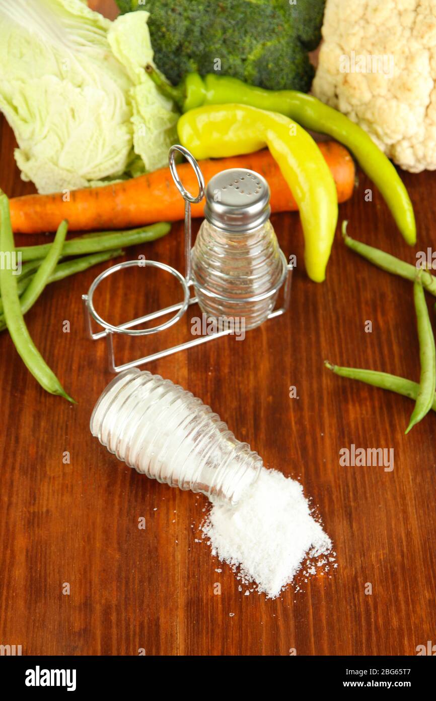 Composition of salt and pepper mills and fresh vegetables, on wooden ...