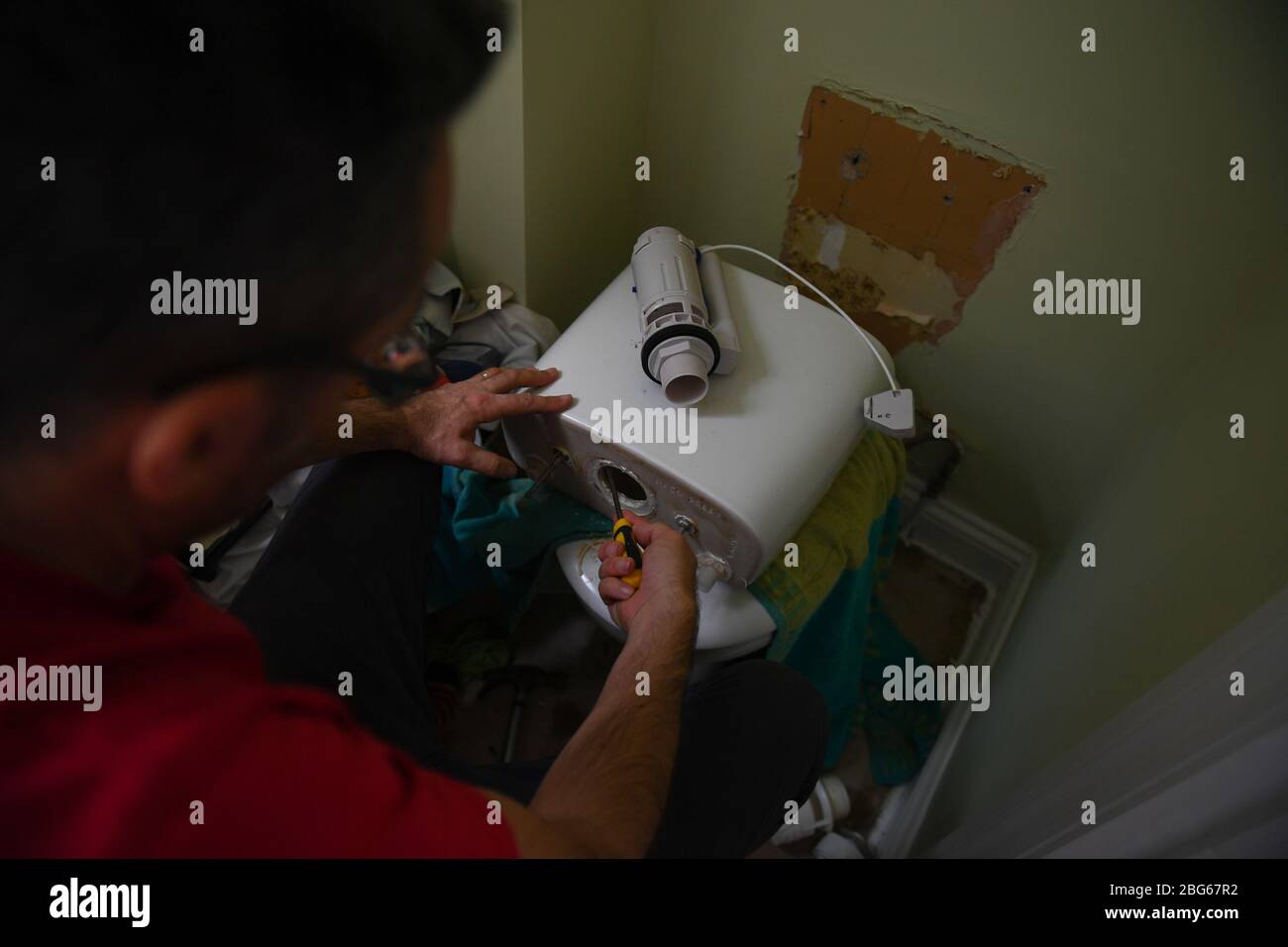 Lockdown DIY, A man fixes a toilet flush mechanism by replacing it with ...