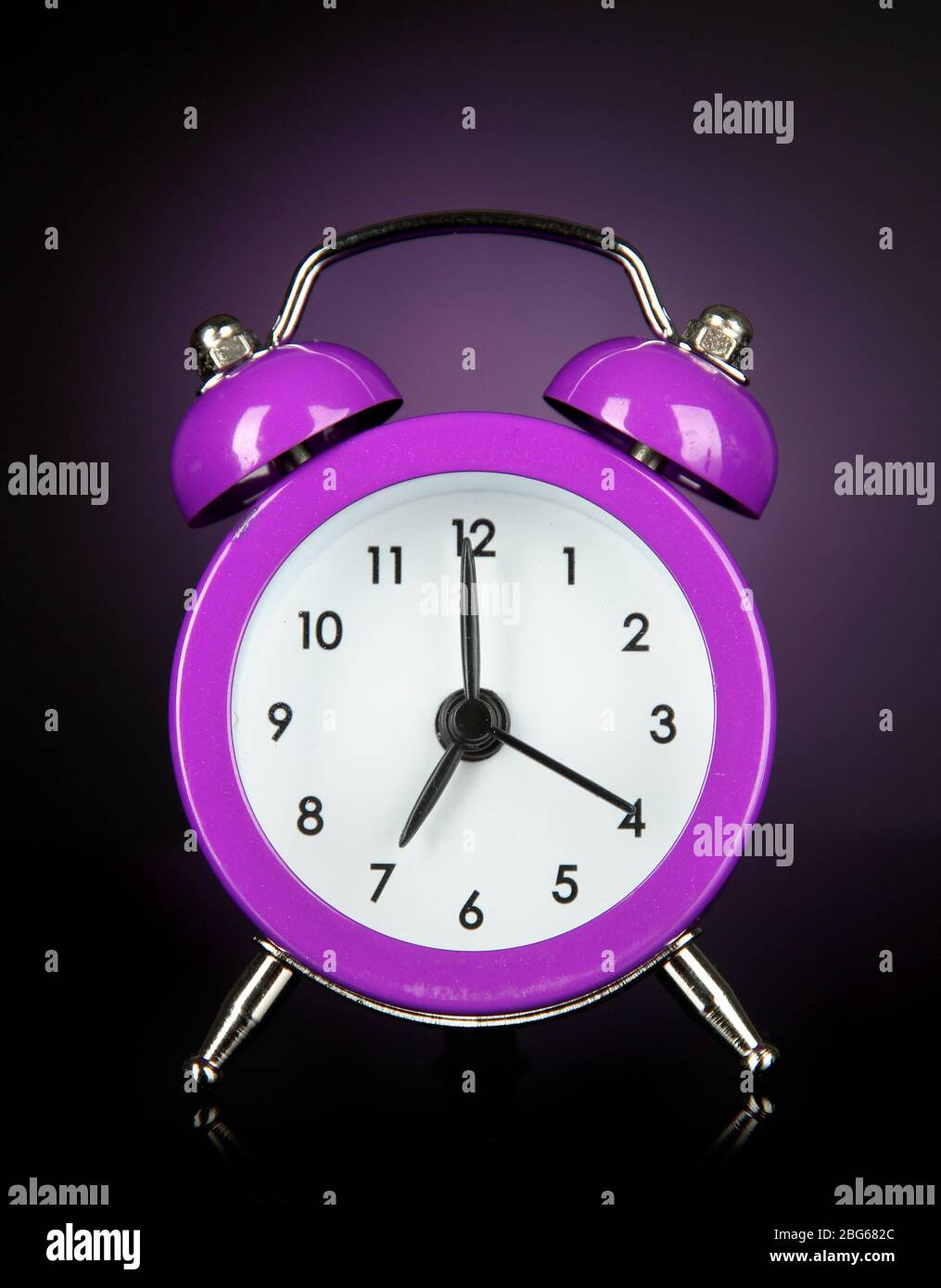 Purple alarm clock on dark purple background Stock Photo - Alamy