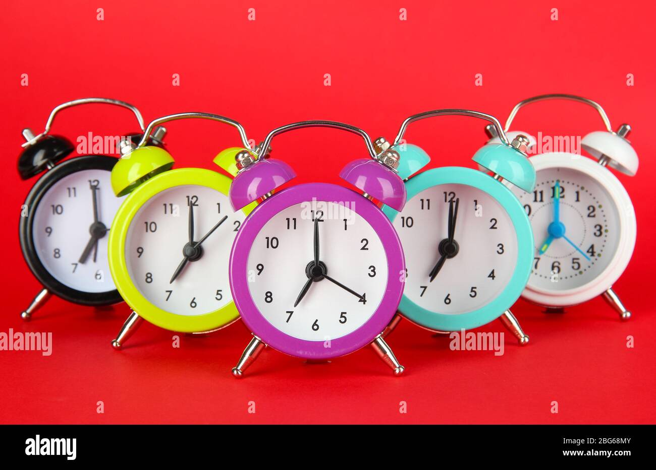 Colorful alarm clock on red background Stock Photo - Alamy