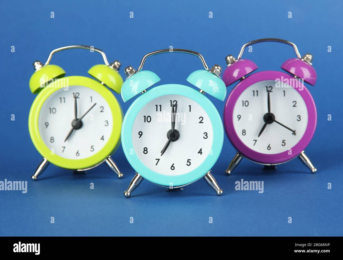 Colorful alarm clock on blue background Stock Photo - Alamy