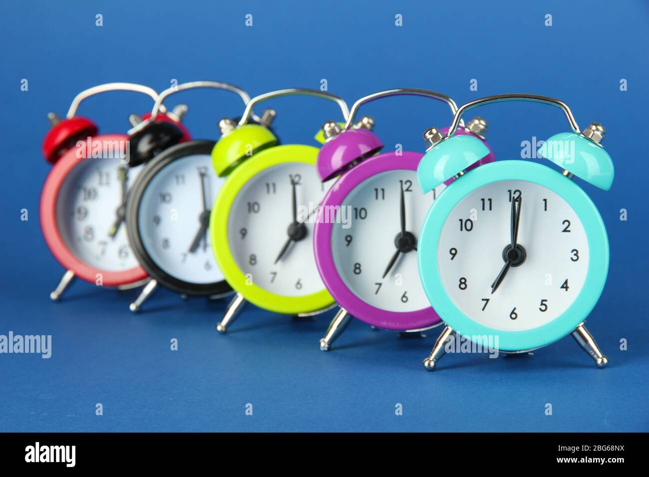 Colorful alarm clock on blue background Stock Photo - Alamy