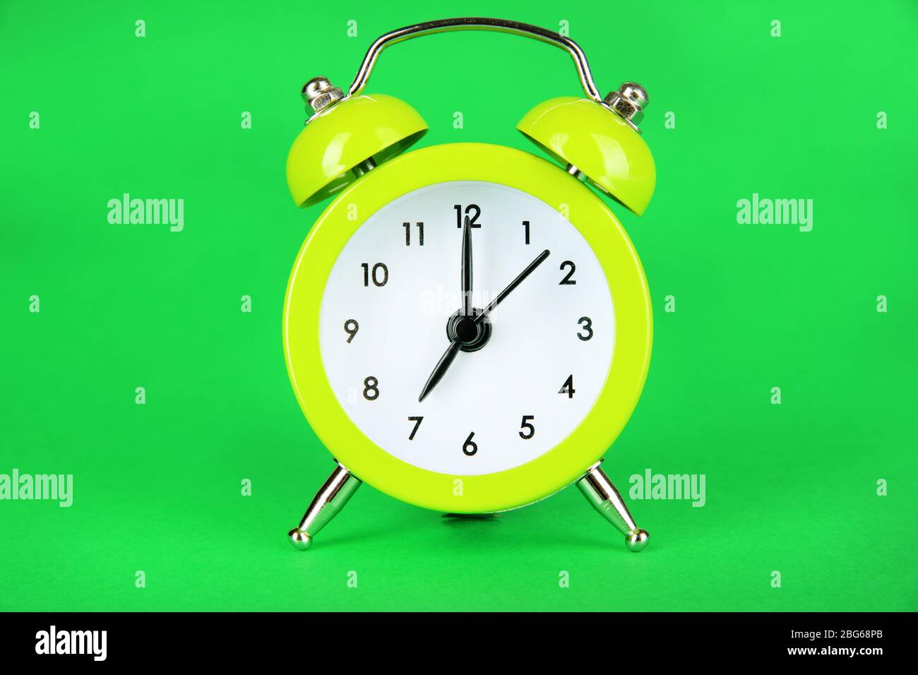 Light green alarm clock on green background Stock Photo - Alamy
