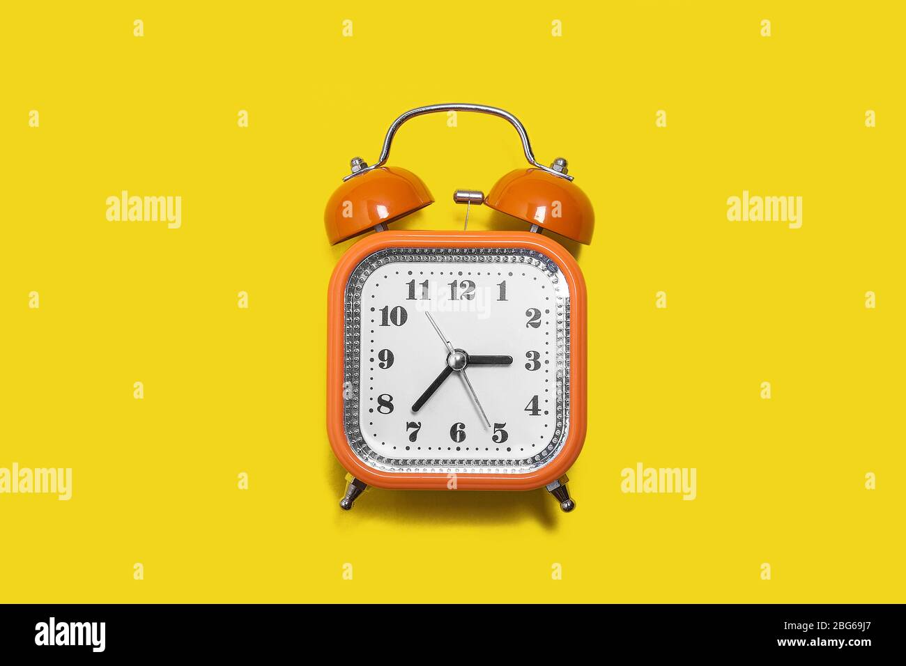 orange alarm clock on the yellow background Stock Photo - Alamy