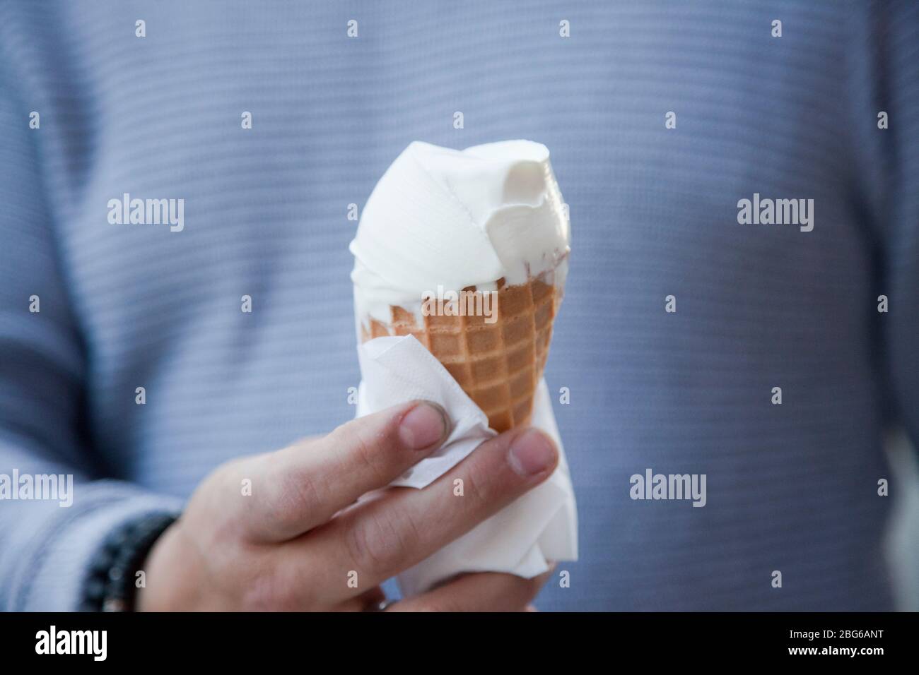 Man in a blue shirt holding a vanilla ice cream cone. Ice cream cone ...