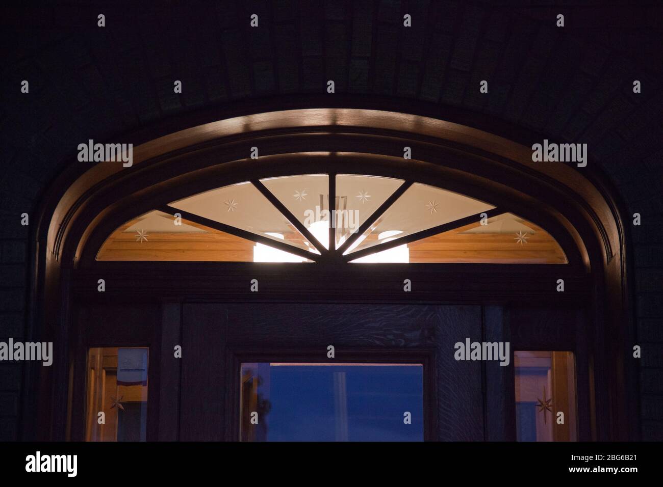 Beautiful illuminated brown wood arched window at twilight with a ...