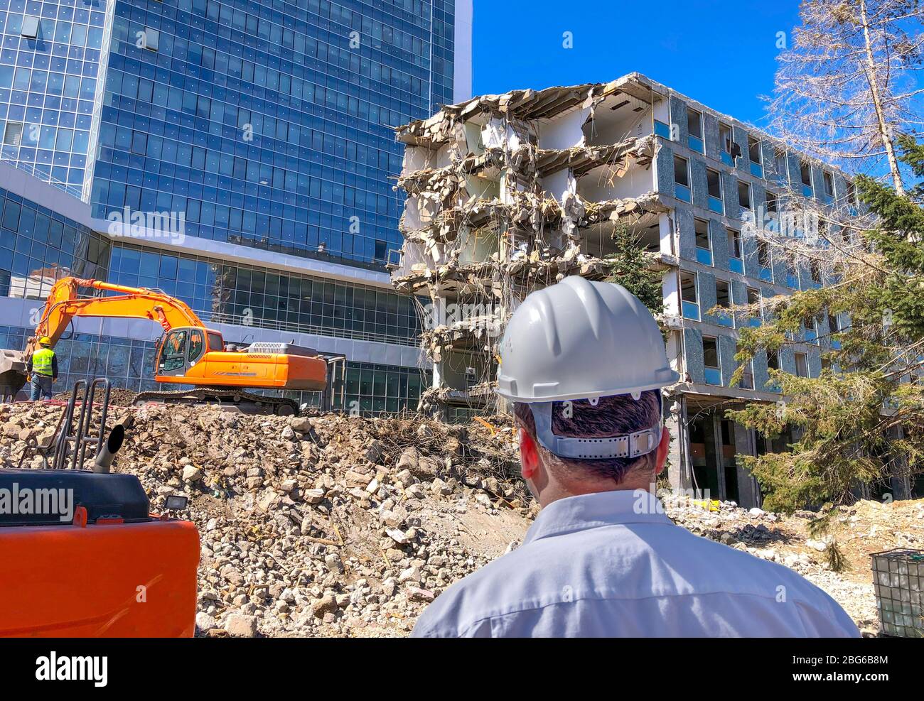 White helmet engineer watches and excavator working at the demolition ...