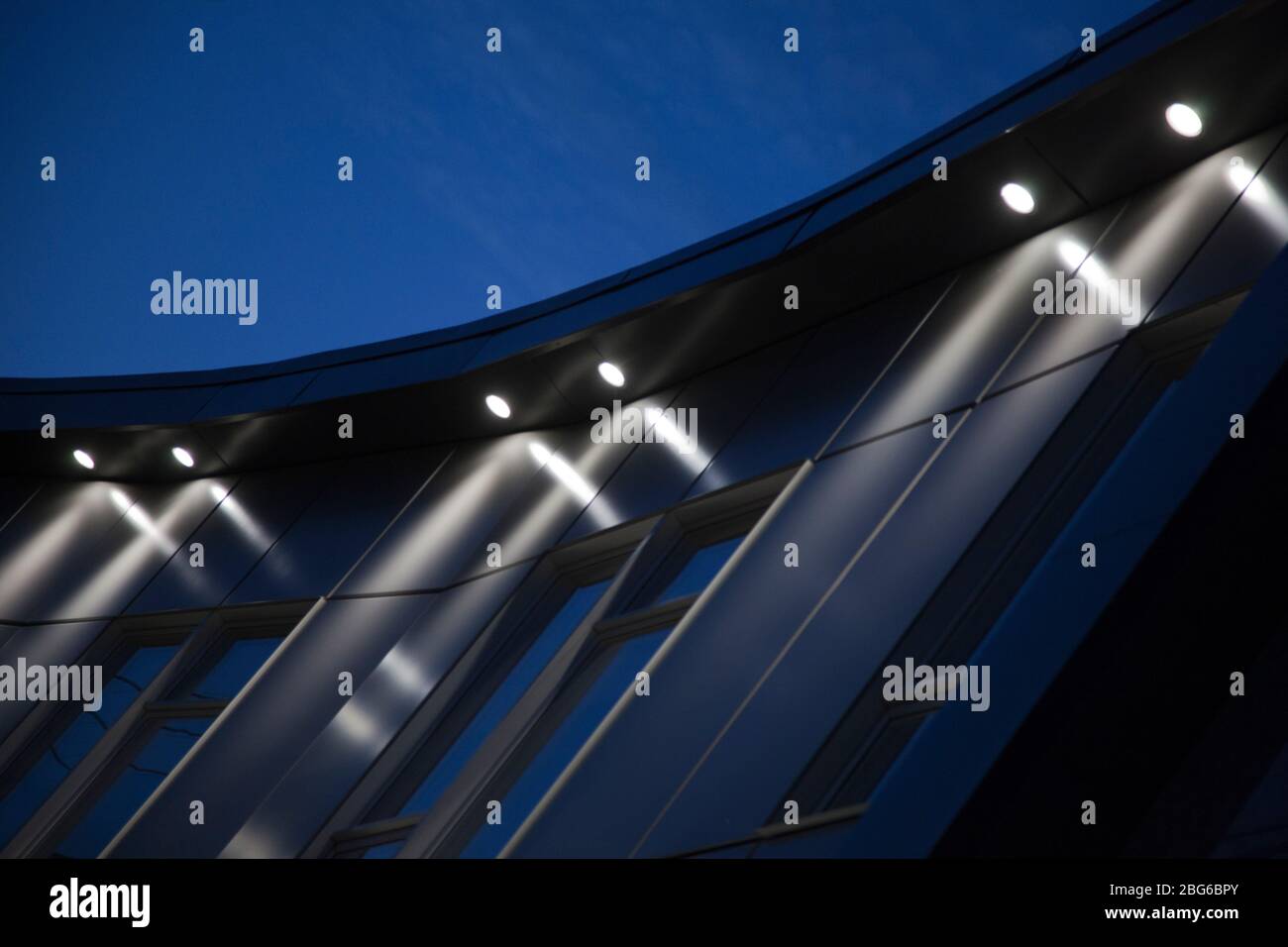 Bright pot lights illuminating a concrete a modern building facade at ...