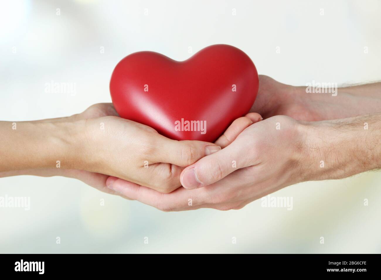 Heart in hands on light background Stock Photo - Alamy