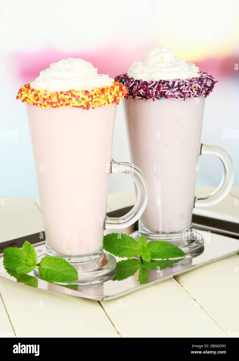 Delicious milk shakes on table on light background Stock Photo - Alamy