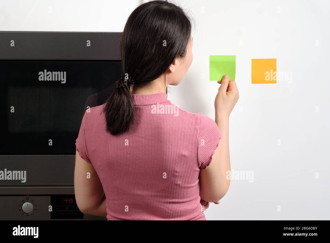 Oriental young woman sticking multicolored generic reminder notes onto ...