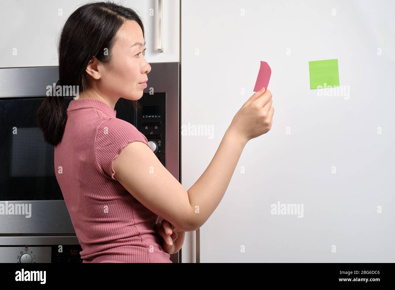 Oriental young woman sticking multicolored generic reminder notes onto ...