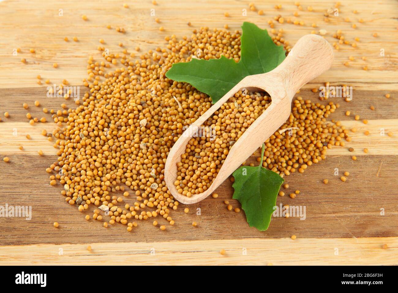 Mustard seeds with mustard leaves on wooden background Stock Photo - Alamy