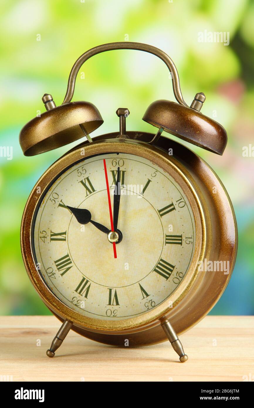 Old alarm clock on bright background Stock Photo - Alamy