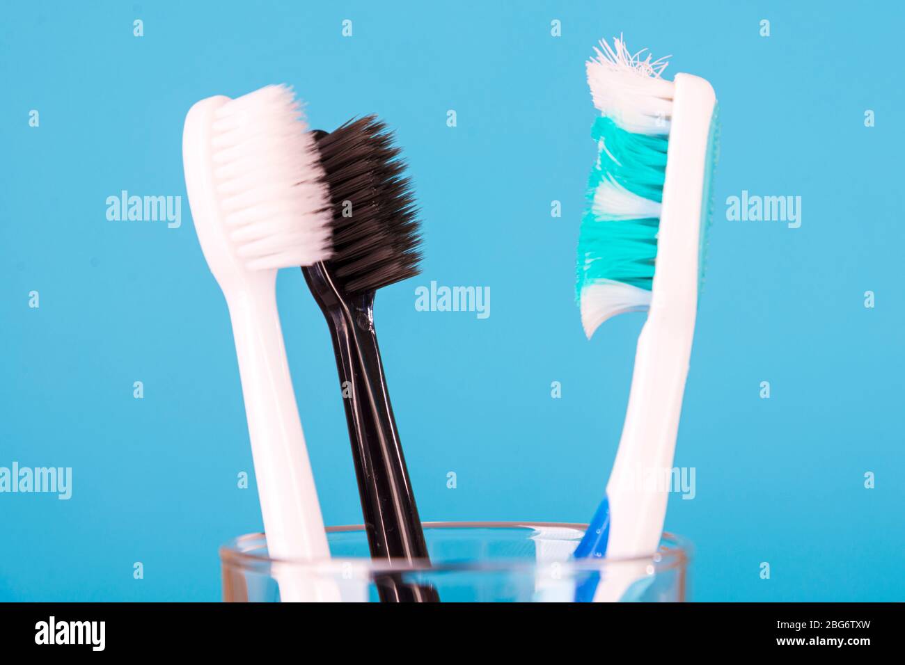 A new toothbrush and an old damaged toothbrush in a glass from a ...