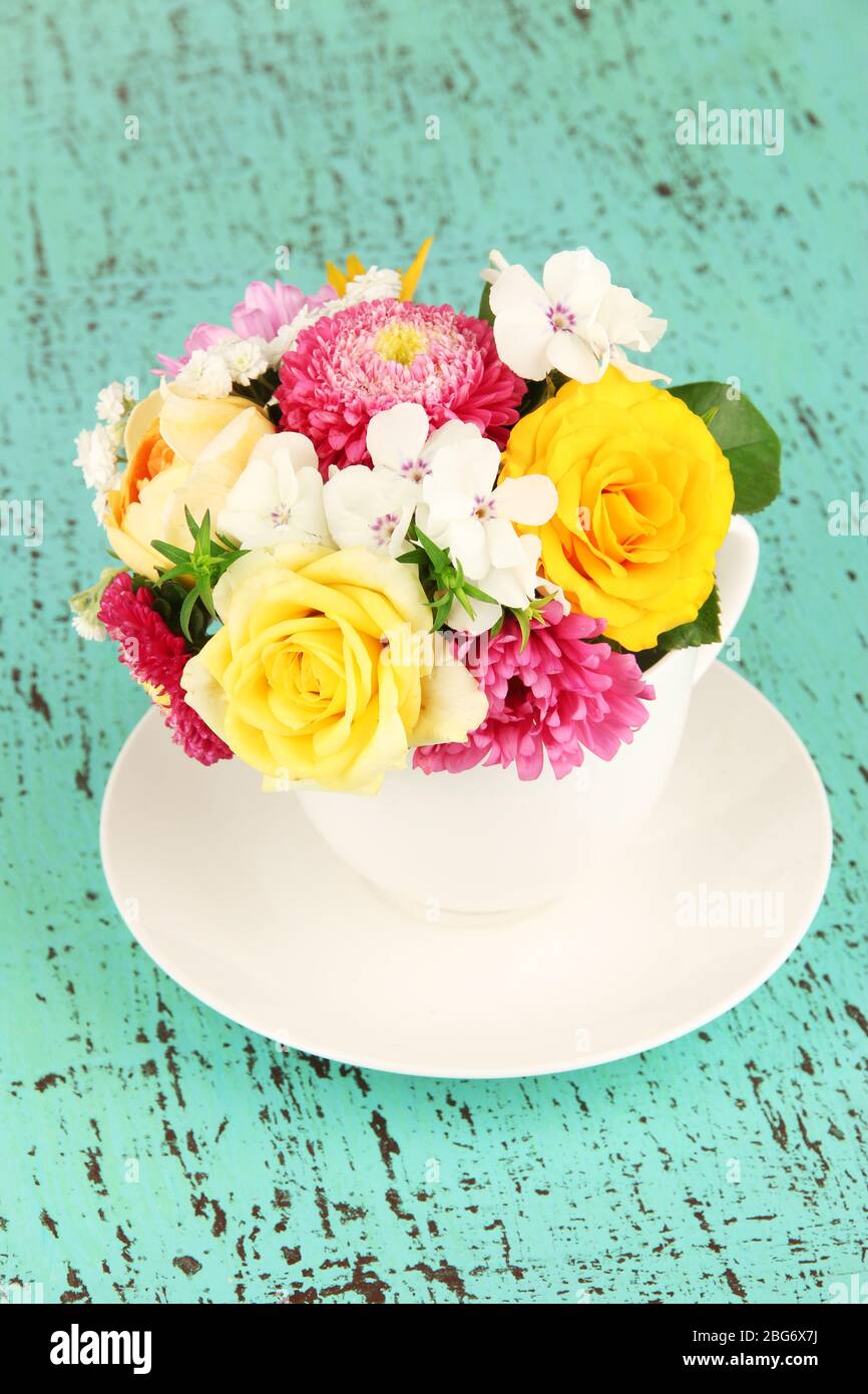Beautiful bouquet of bright flowers in color vase, on bright background ...