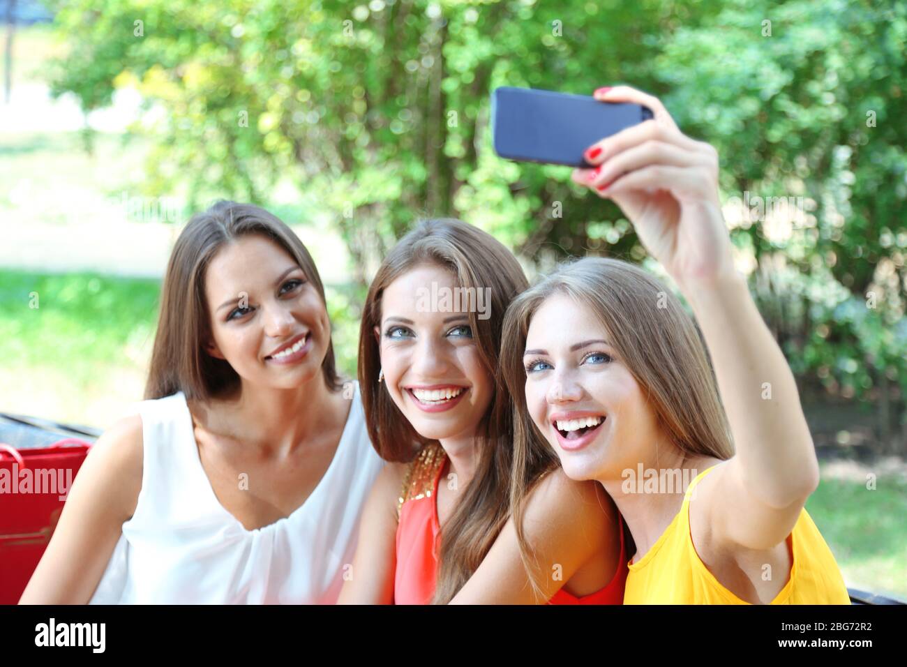 Three beautiful young woman taking picture in summer park Stock Photo ...