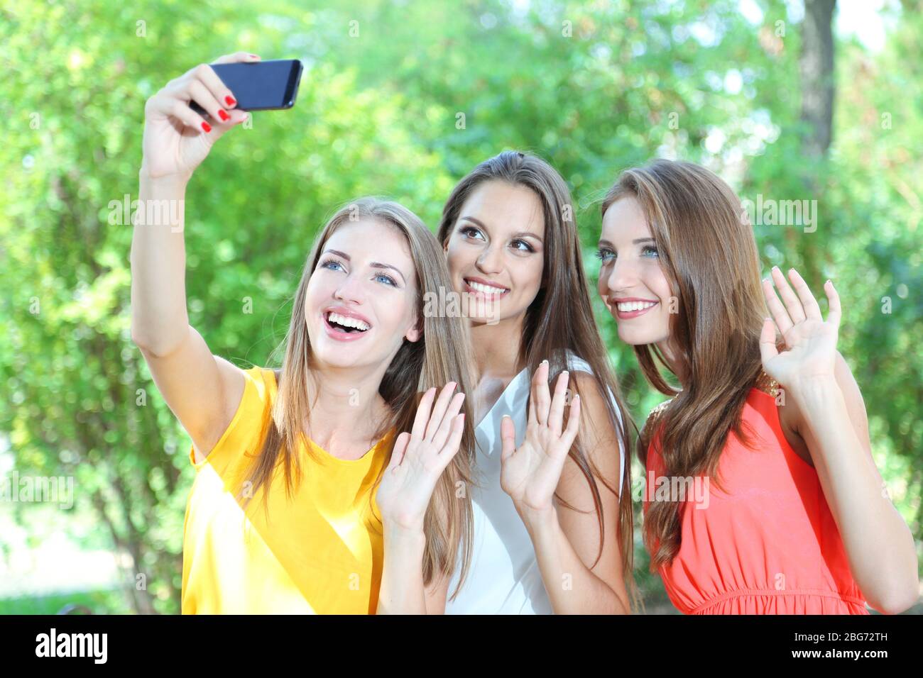 Three beautiful young woman taking picture in summer park Stock Photo ...
