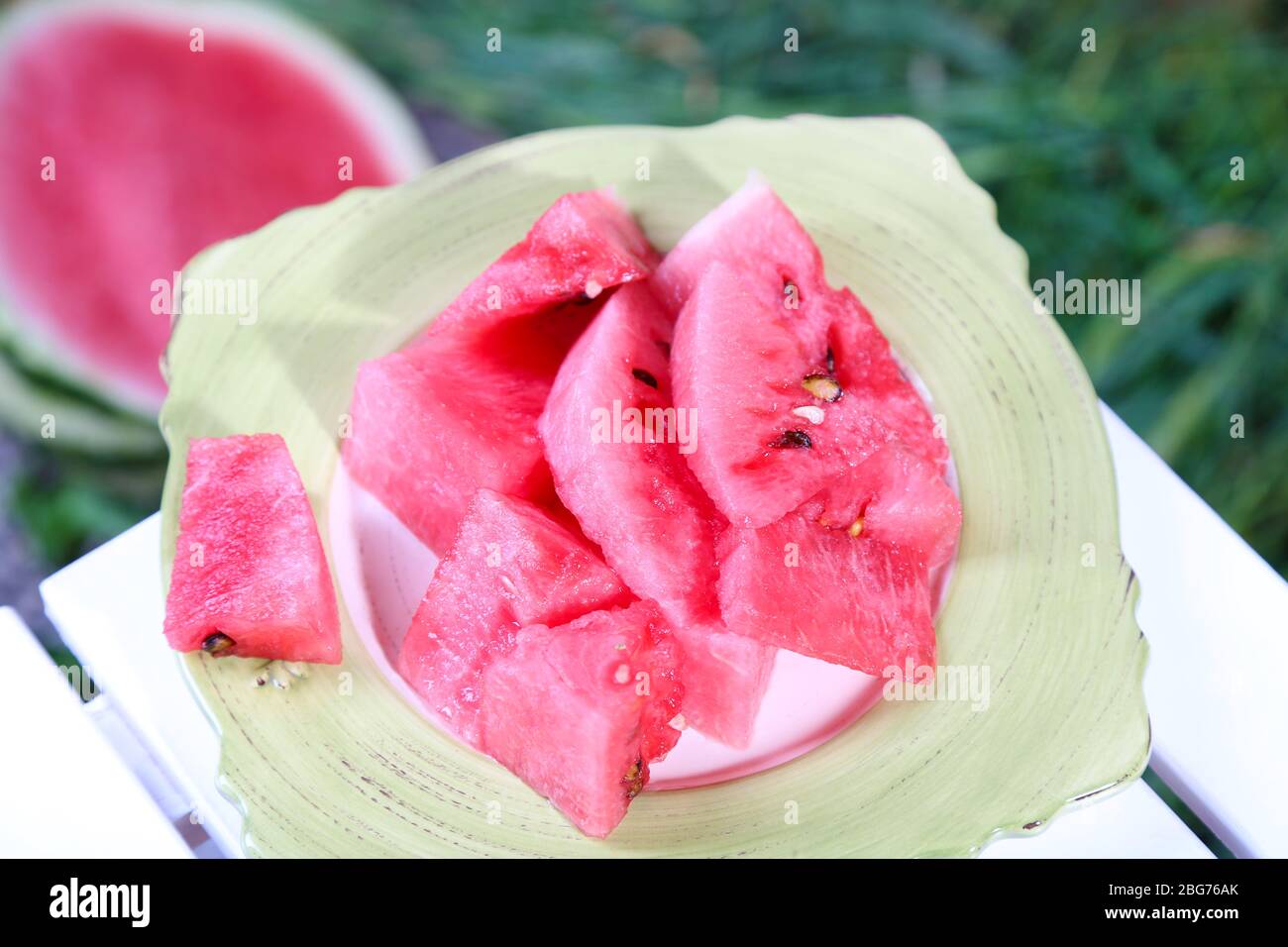 Watermelon slices on plate on table on grass background Stock Photo - Alamy