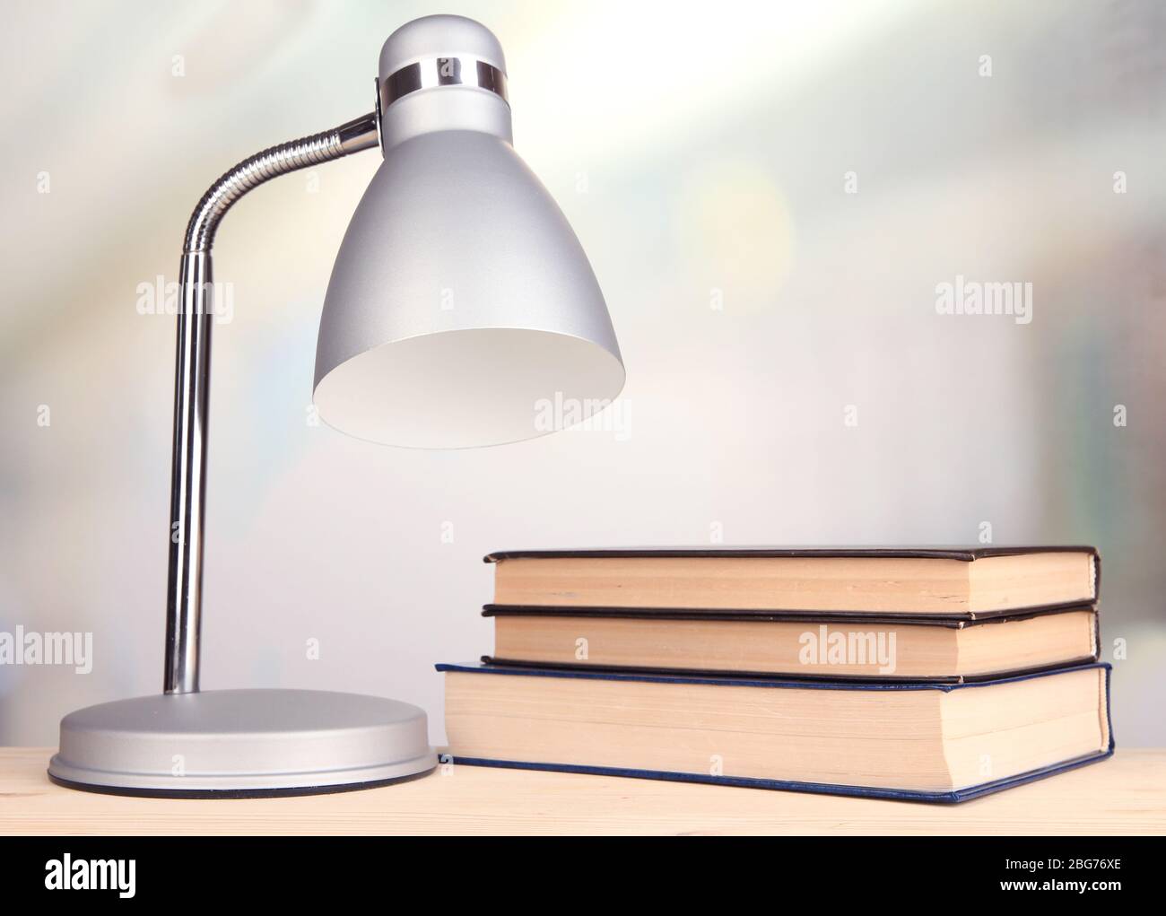 Table lamp and books on desk in room Stock Photo - Alamy