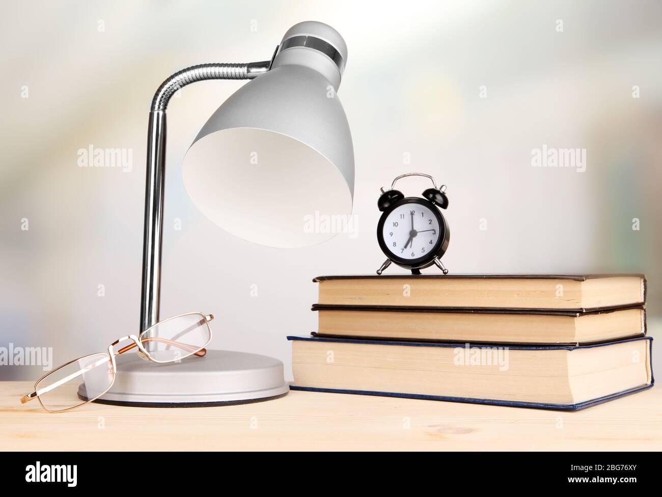 Table lamp and books on desk in room Stock Photo - Alamy
