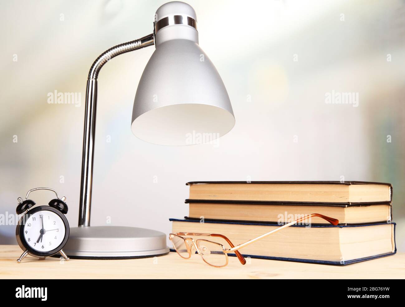 Table lamp and books on desk in room Stock Photo - Alamy