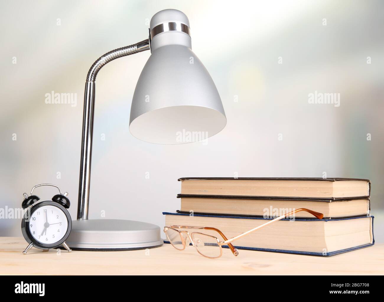 Table lamp and books on desk in room Stock Photo - Alamy