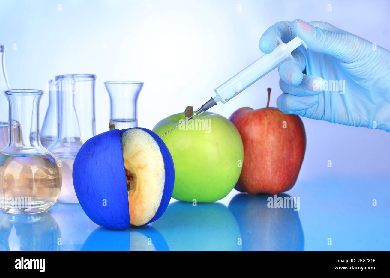 Injection into apple on blue background Stock Photo - Alamy