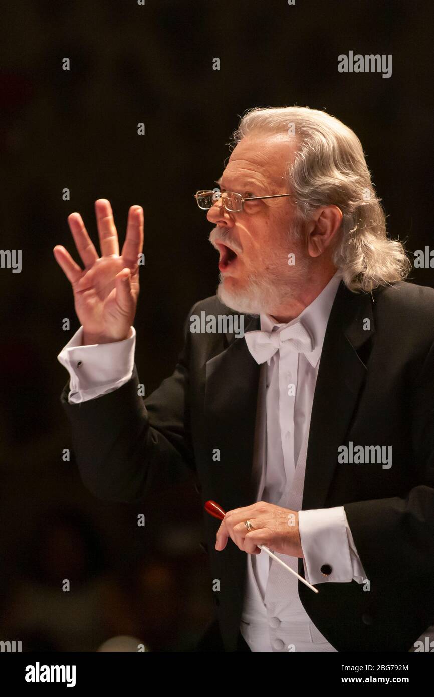 Conductor (model released) directs classical orchestra in performance ...