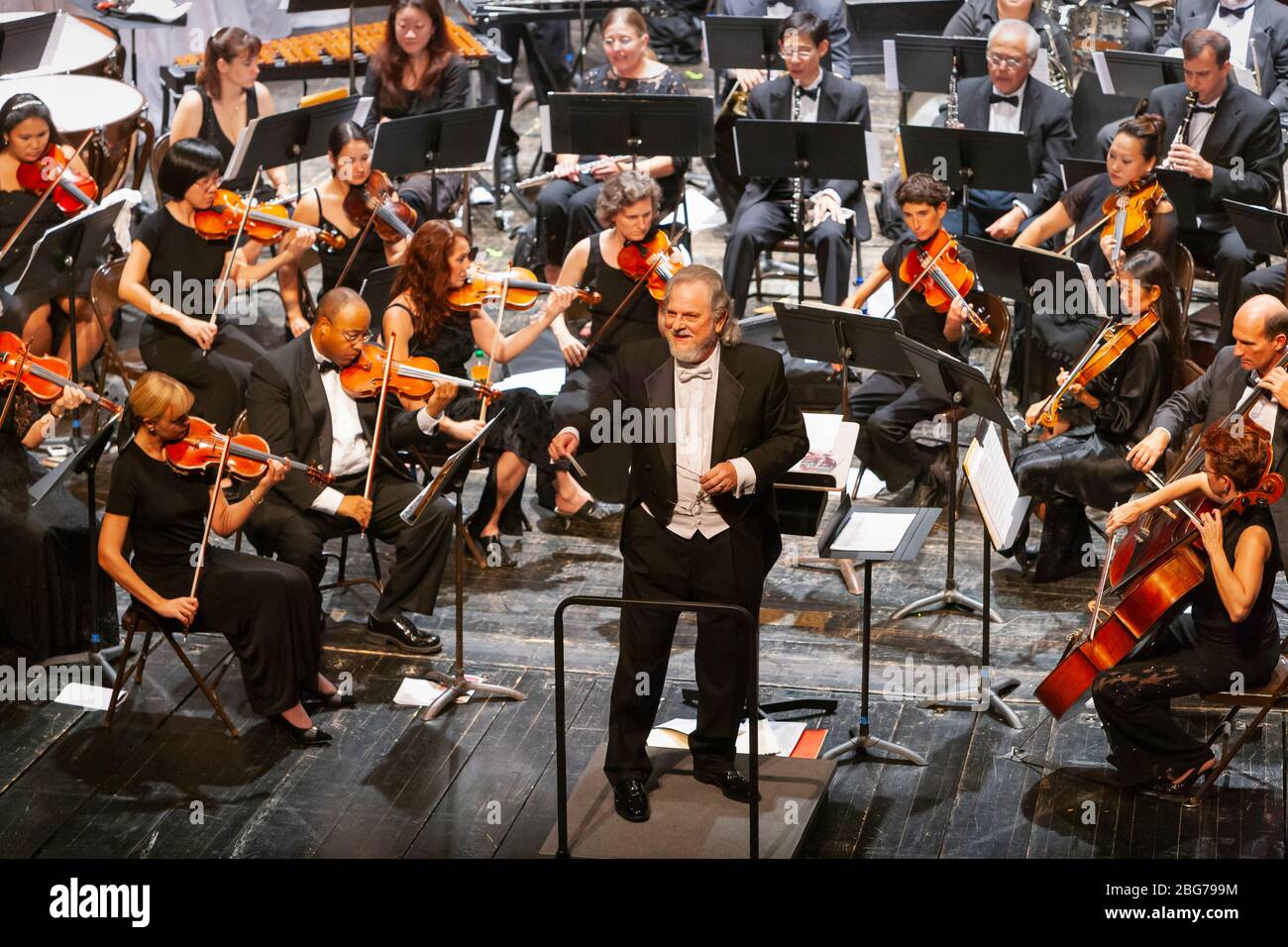 Conductor of classical orchestra (all model released) leads audience in ...