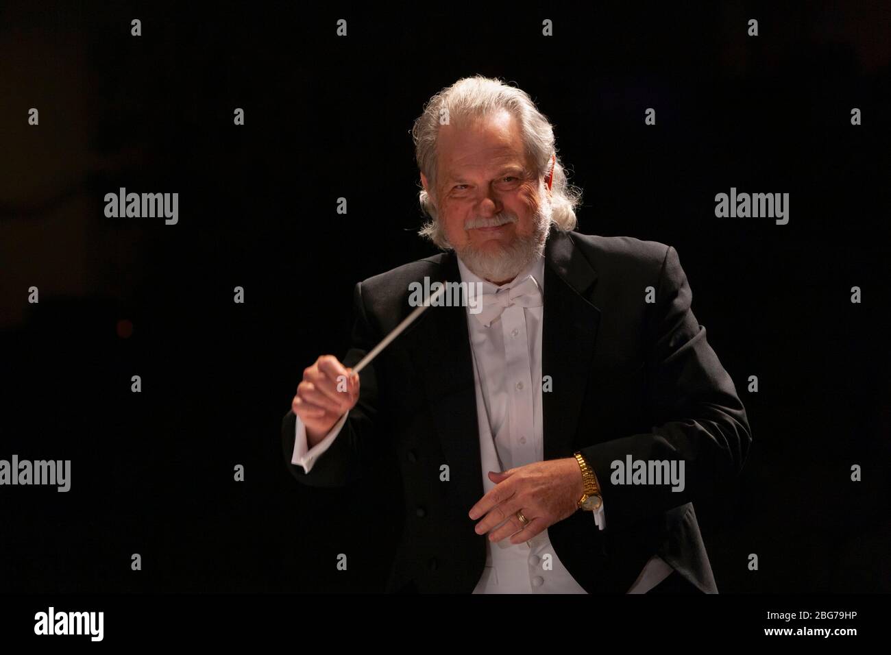 Conductor (model released) directs classical orchestra in performance ...