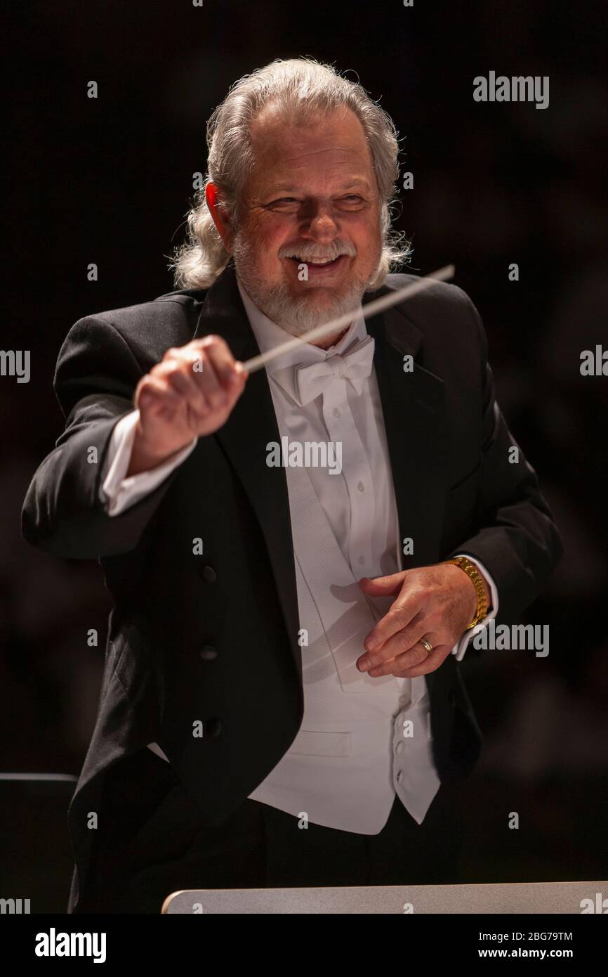 Conductor (model released) directs classical orchestra in performance ...