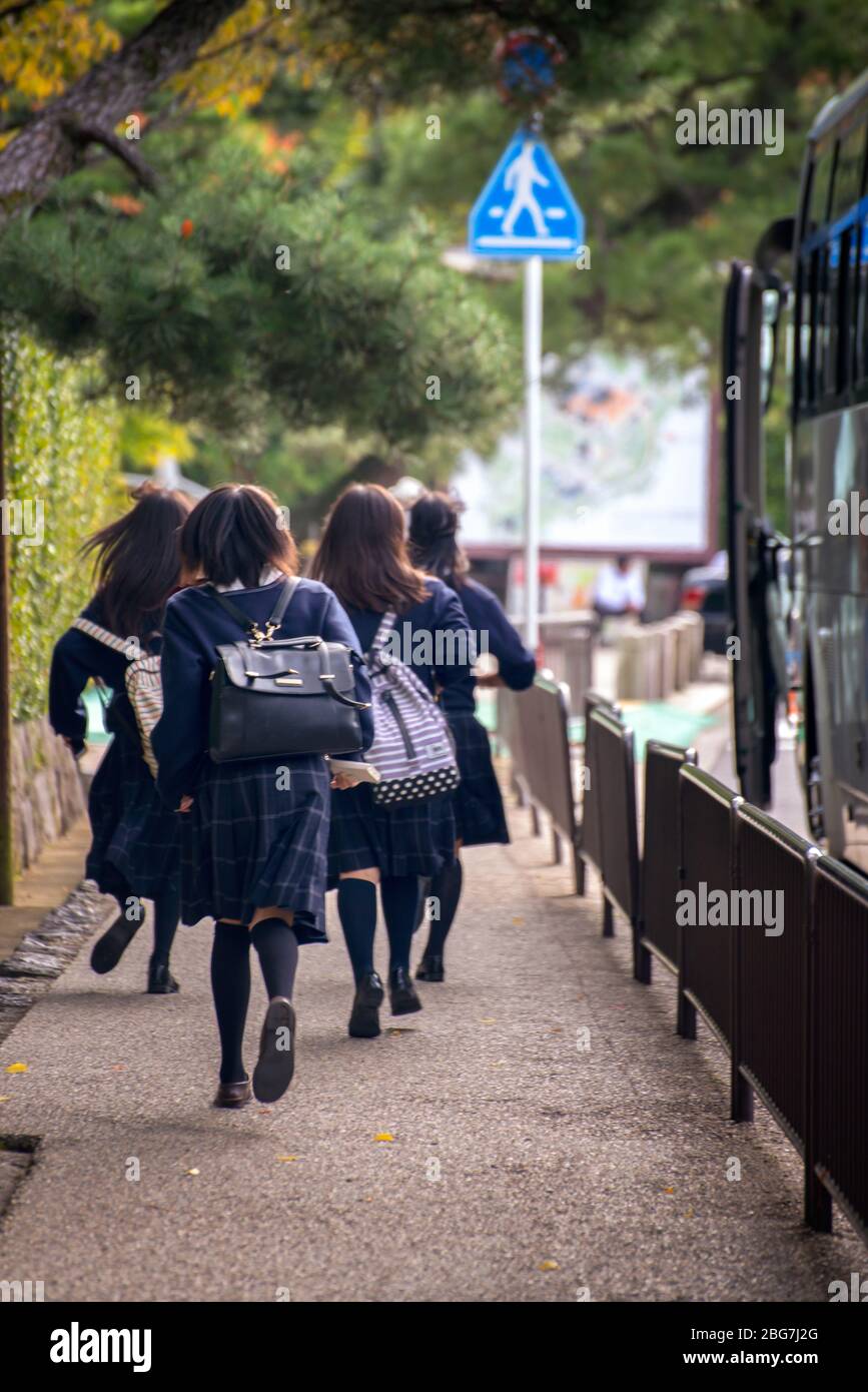 Schoolgirls running to catch a city bus along Shishigatani Dori in ...