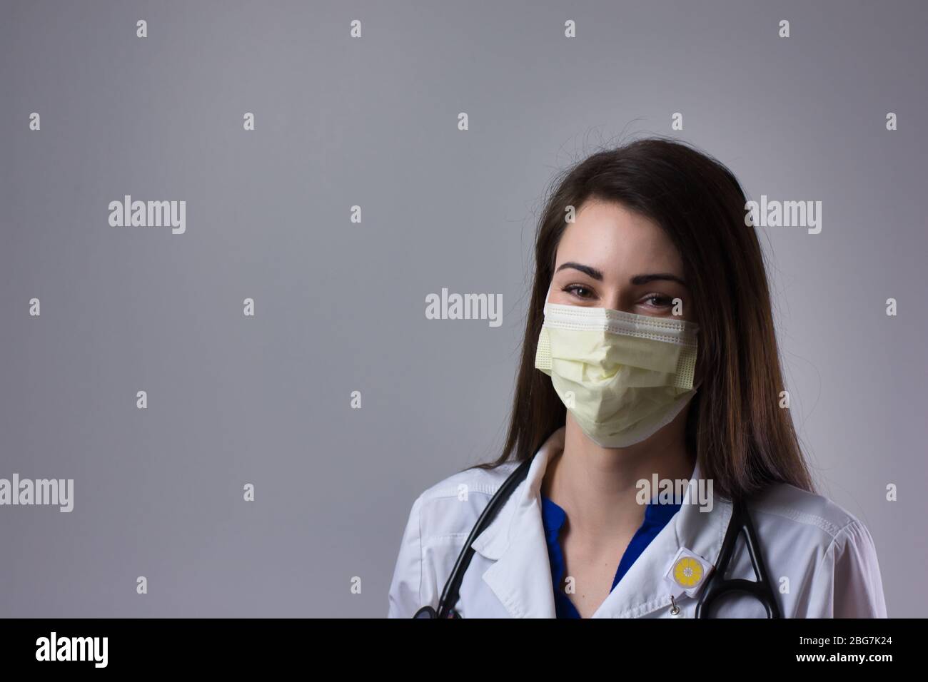 Masked woman medical professional smiling under mask. Isolated on grey ...