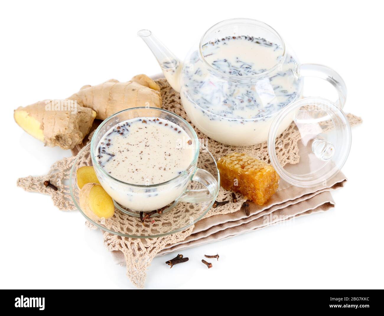 Teapot and cup of tea with milk and spices on napkin isolated on white ...