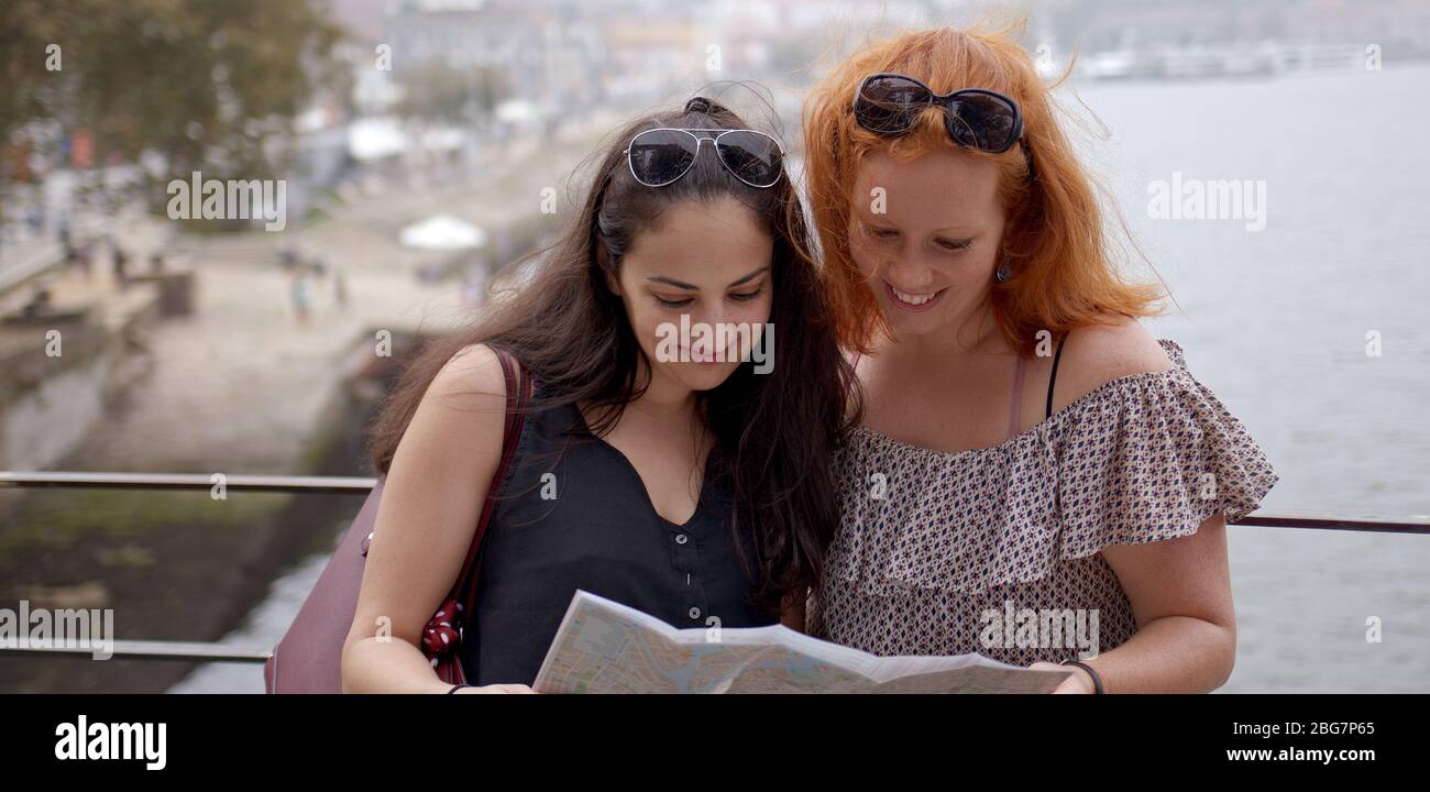 Two girls checking destinations on a map Stock Photo - Alamy