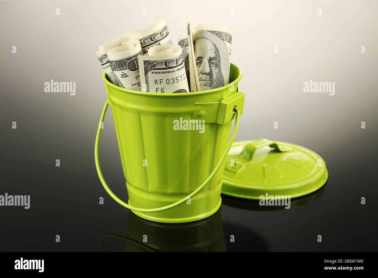 Money in trash can, on dark background Stock Photo - Alamy