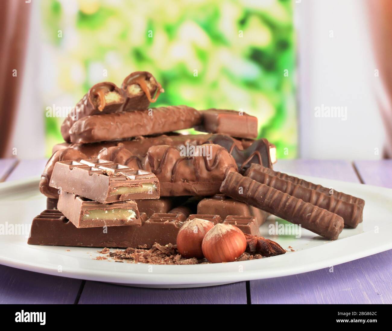Plate with delicious chocolate bars on table on bright background Stock ...