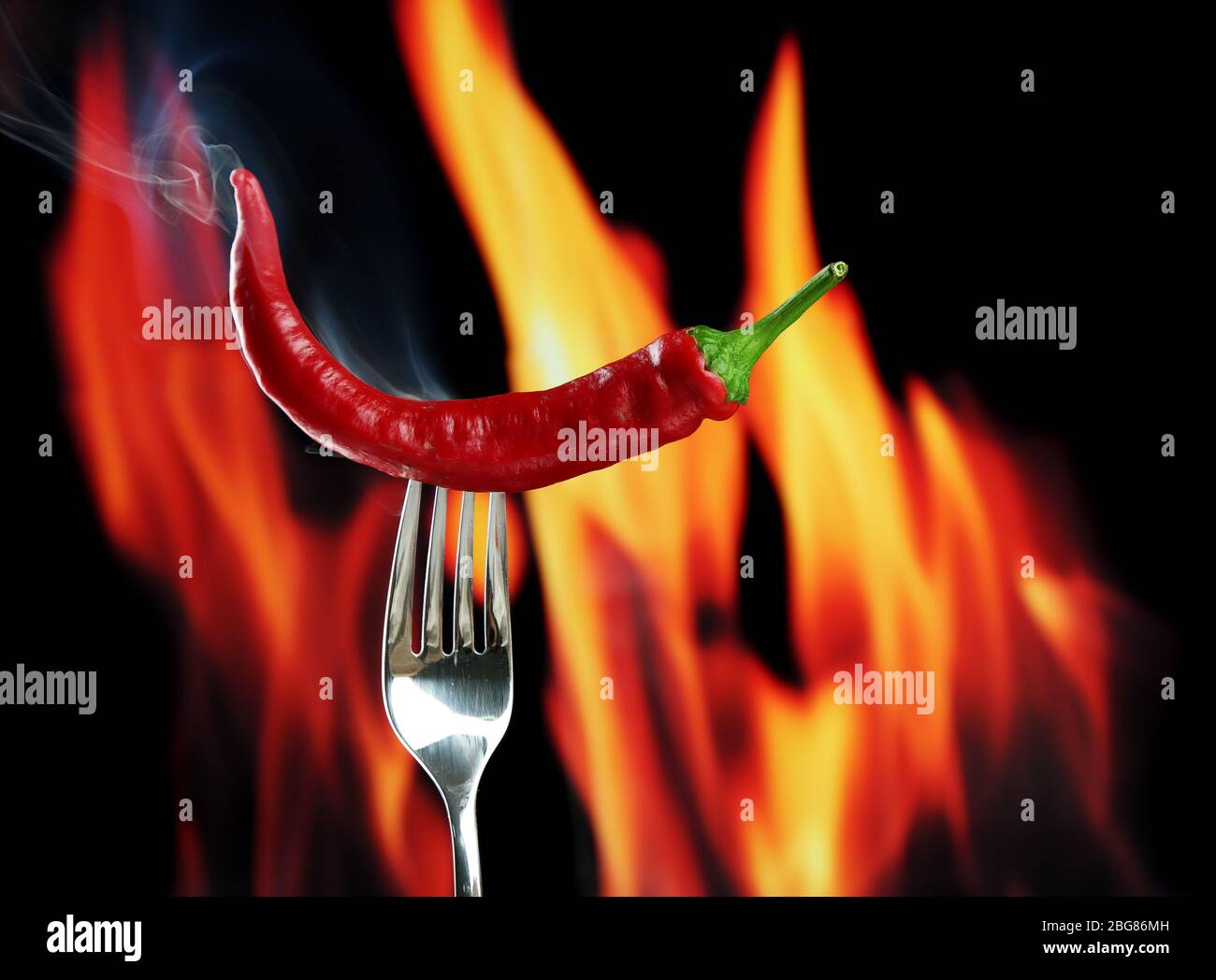 Red hot chili pepper on fork, on fire background Stock Photo - Alamy