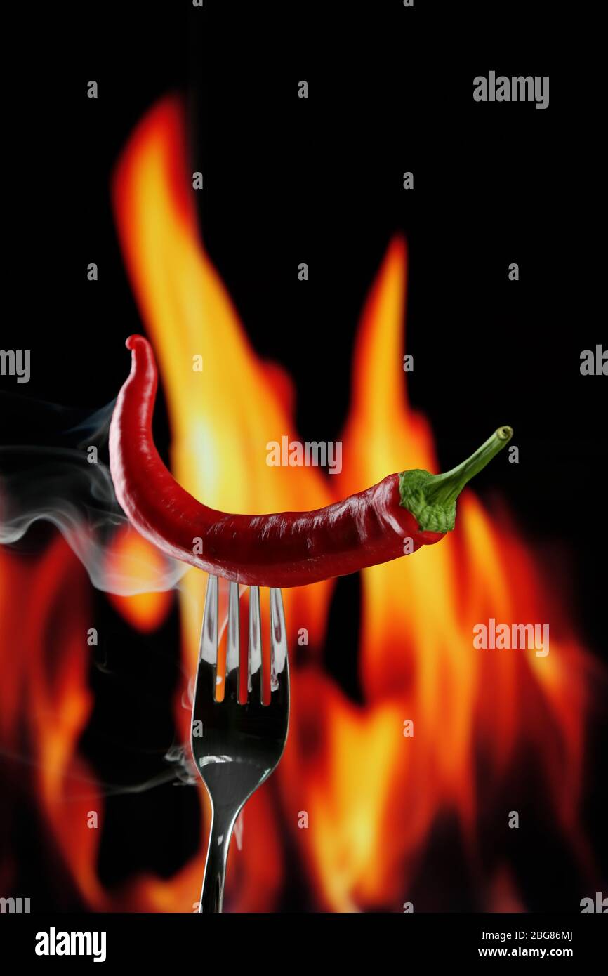 Red hot chili pepper on fork, on fire background Stock Photo - Alamy