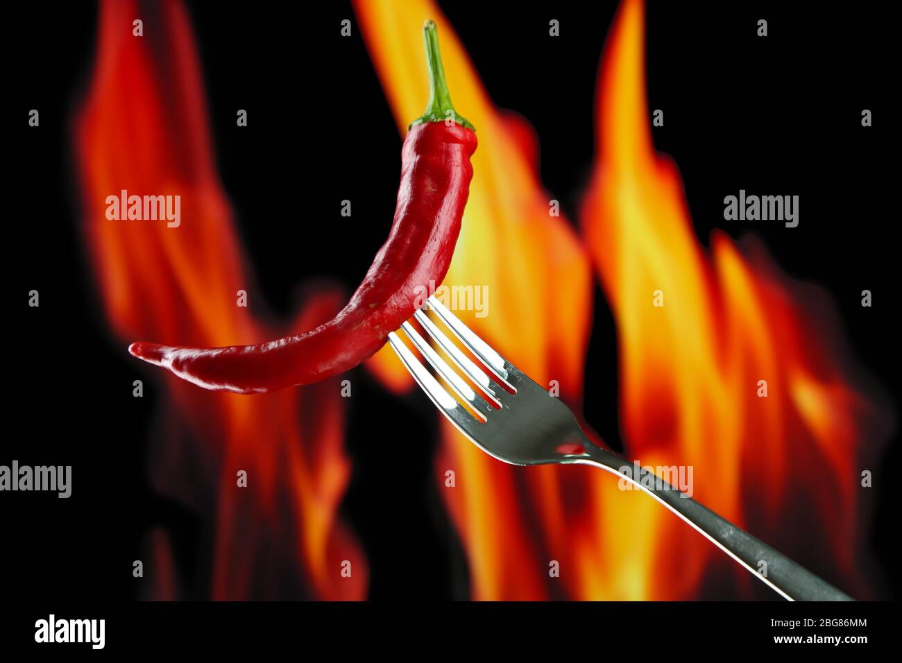 Red hot chili pepper on fork, on fire background Stock Photo - Alamy